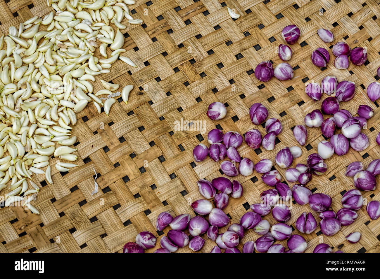 Fresh baby onions and garlic lying on a basket patterned background ...