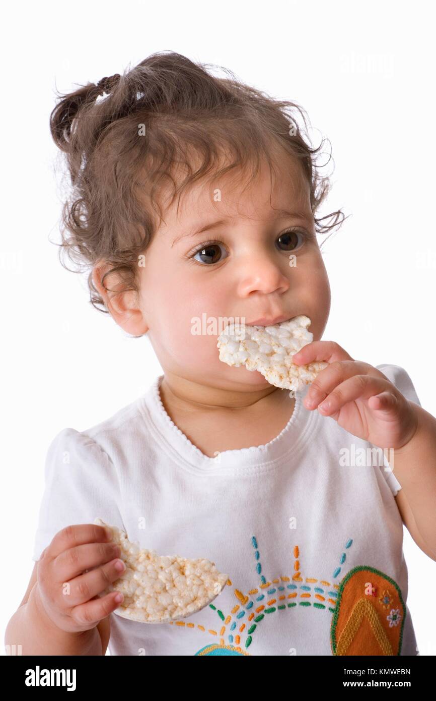 Baby girl is eating a snack on white background Stock Photo - Alamy