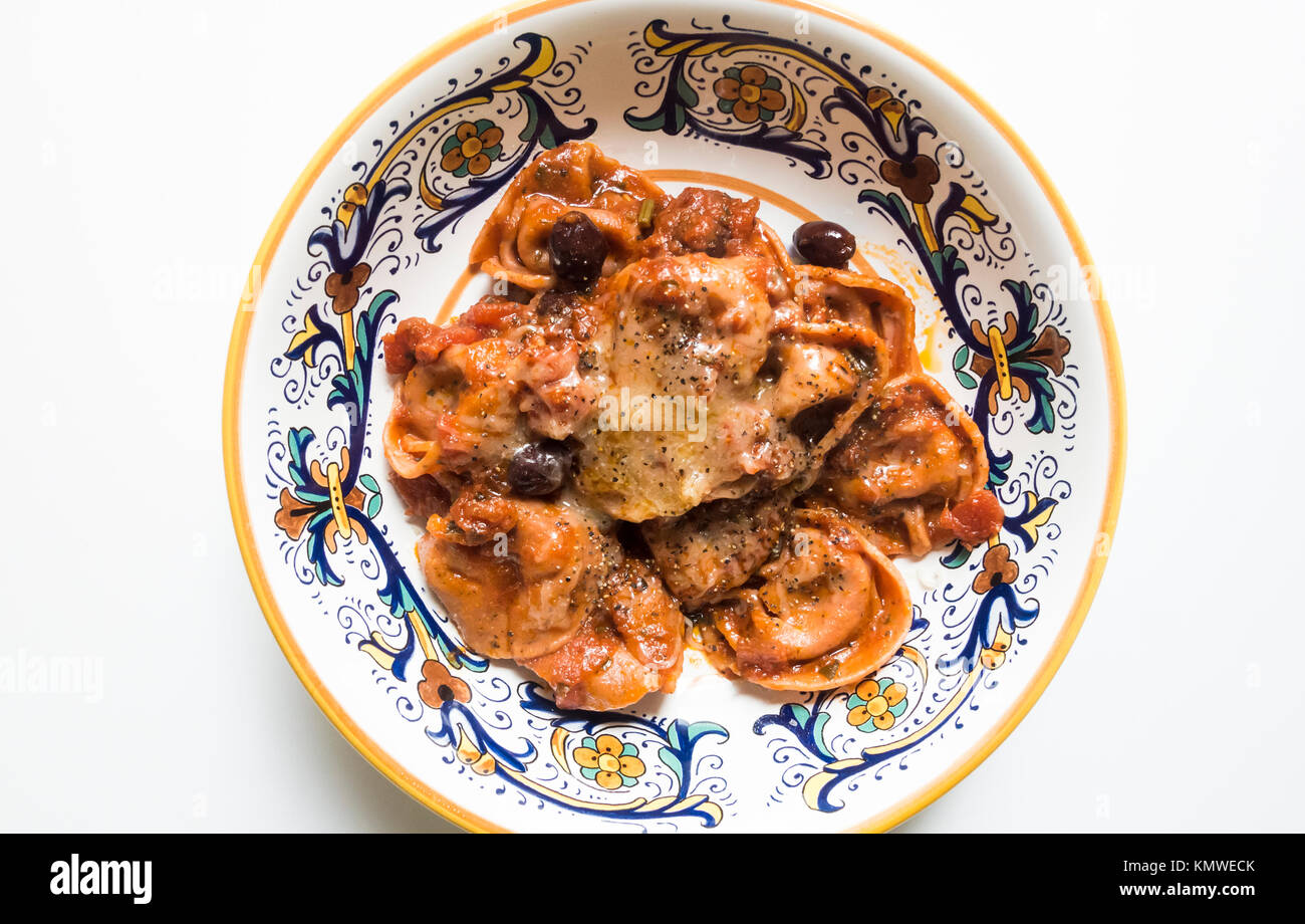 Tortellini, a stuffed half-moon shaped pasta, with tomatoes, olives and ...