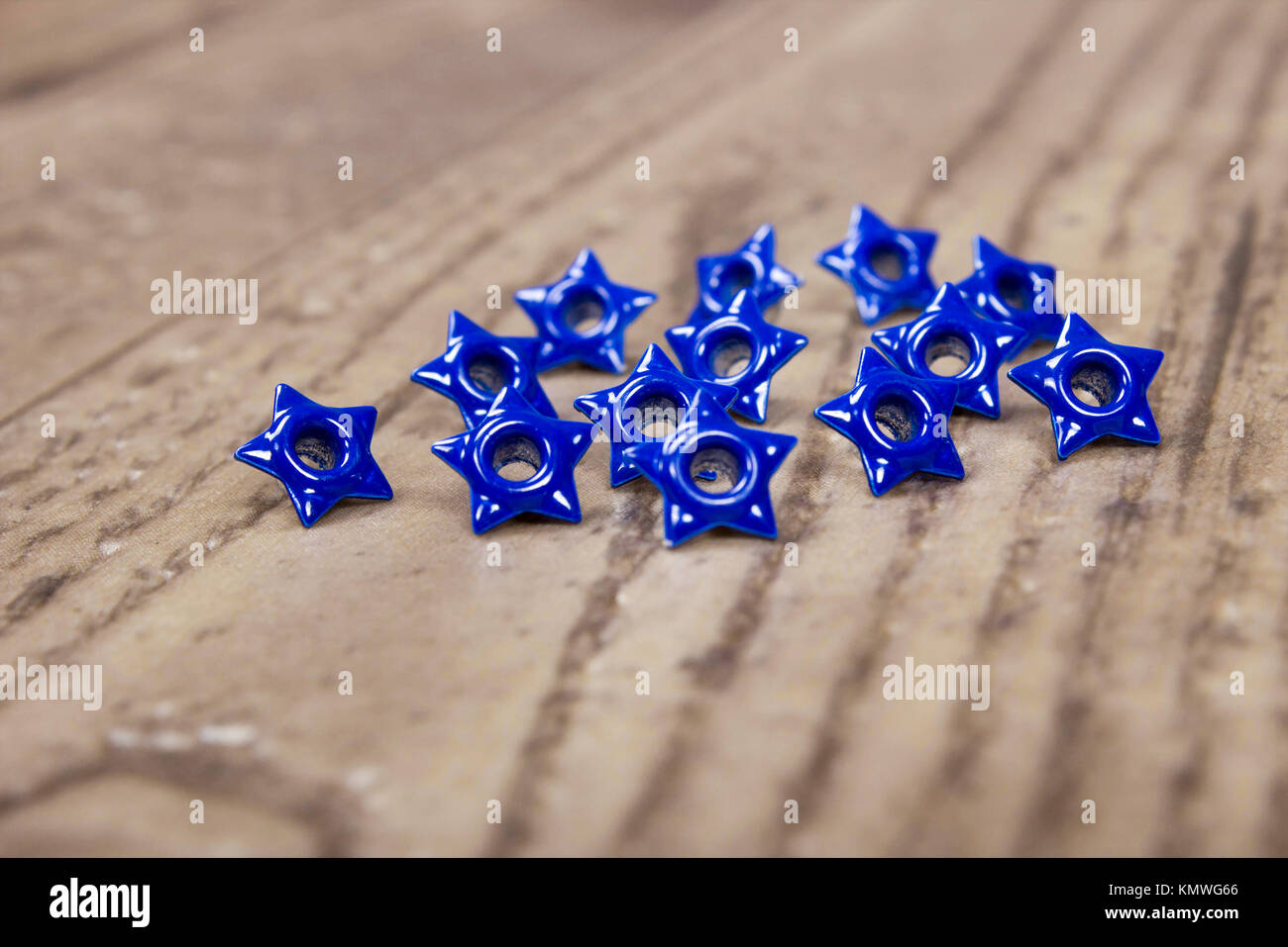 close up of texture and or detail of blue star eyelets laying on wood ...