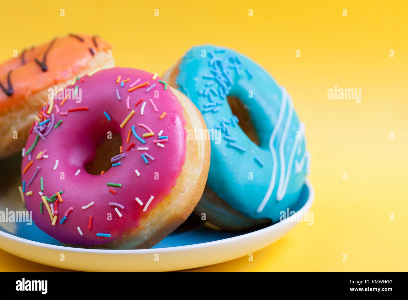 A plate with donuts in the glaze on an orange background Stock Photo ...