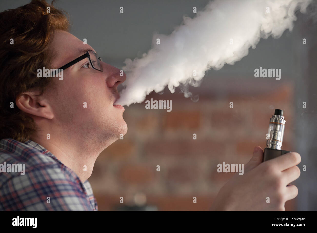 Young man smoking electronic cigarette near window. vaping Stock Photo ...