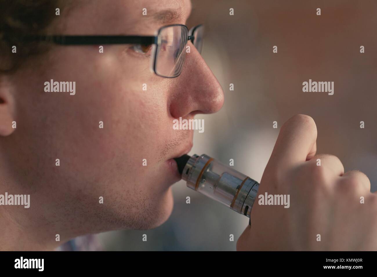 Young man smoking electronic cigarette near window. vaping Stock Photo ...