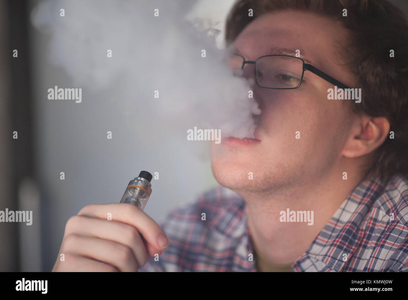 Young man smoking electronic cigarette near window. vaping Stock Photo ...