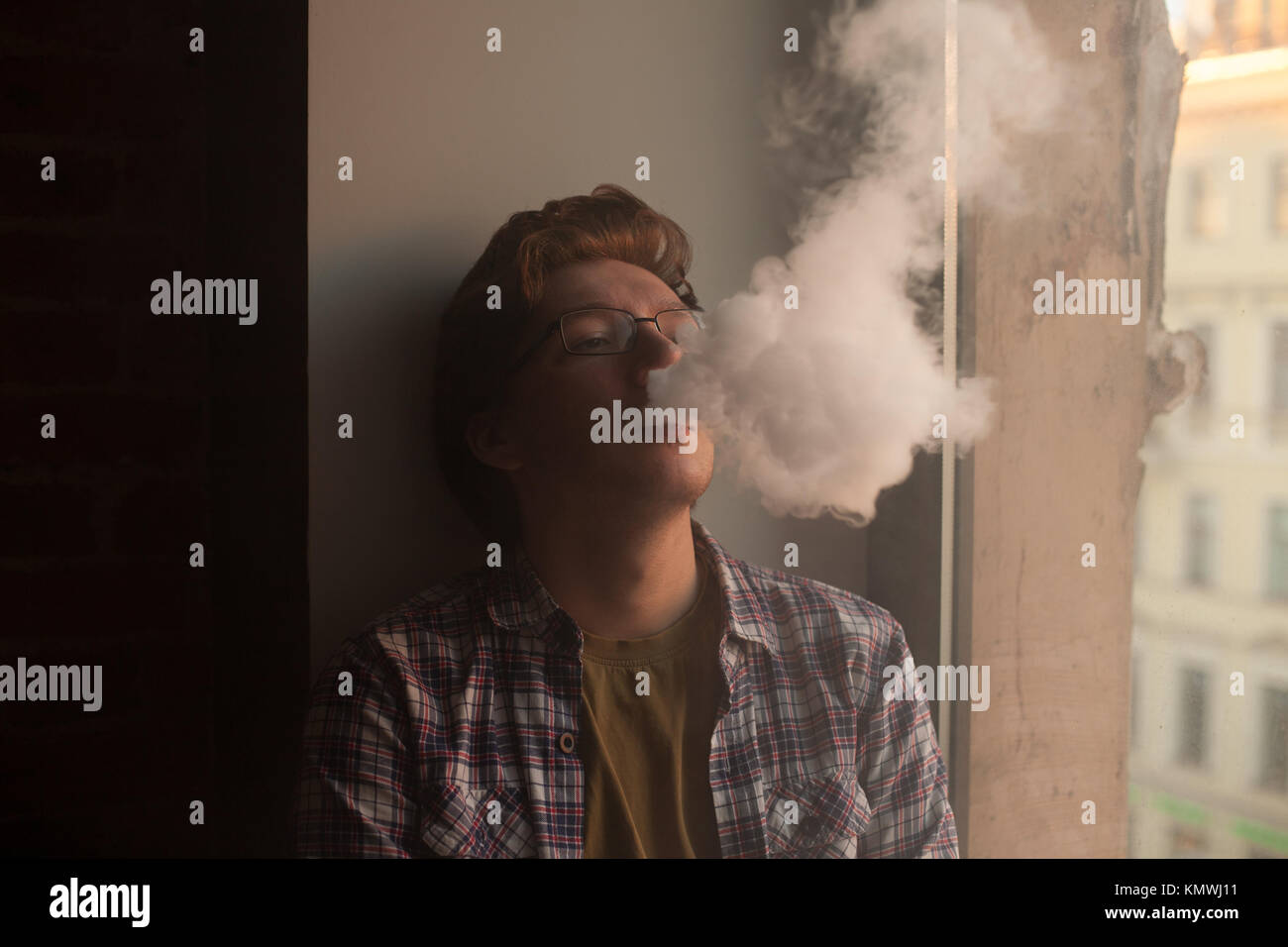 Young man smoking electronic cigarette near window. vaping Stock Photo ...