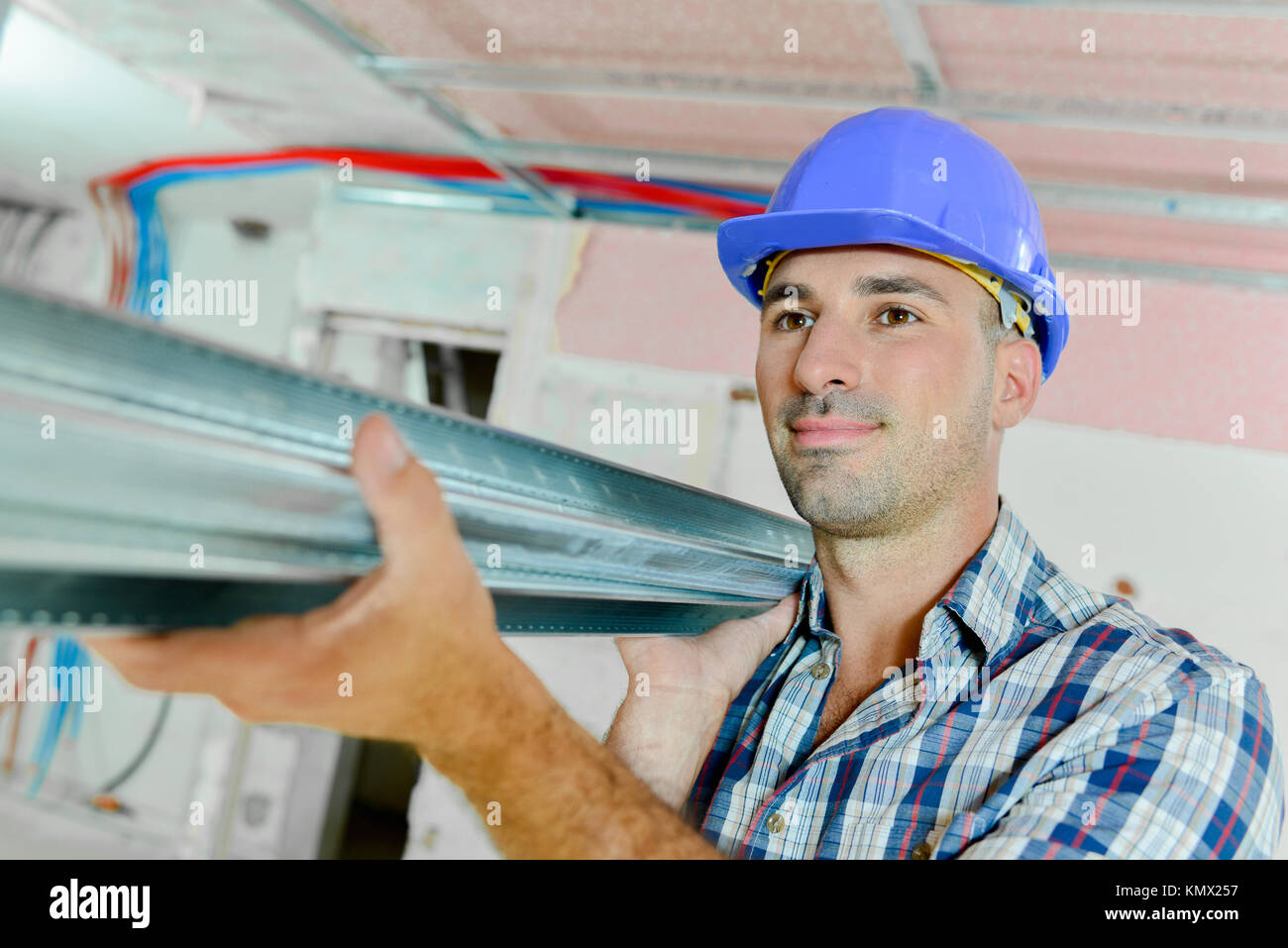 Builder carrying metal lengths on his shoulder Stock Photo - Alamy