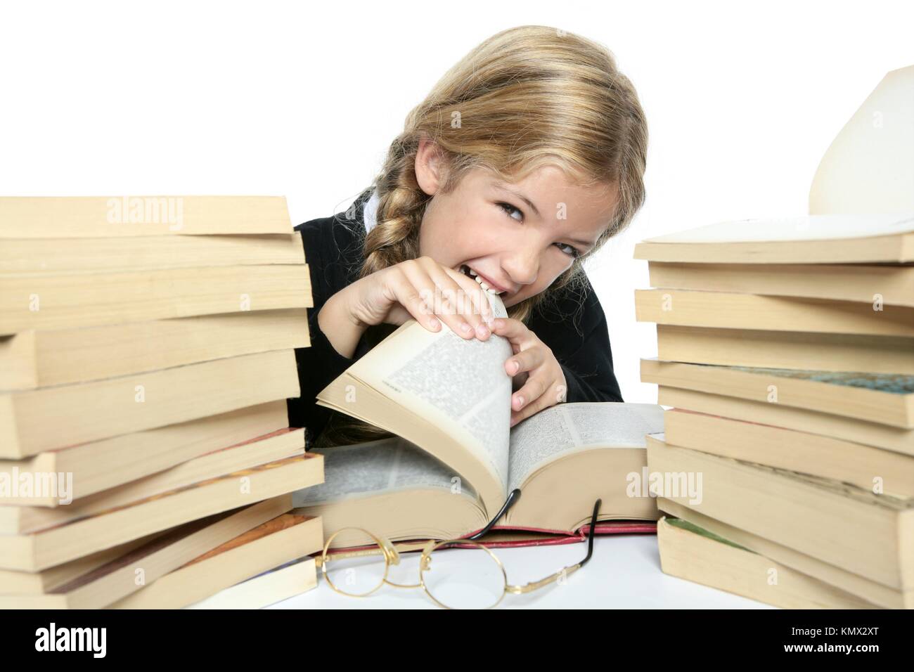 little blond student girl eating her books with a funny gesture Stock ...