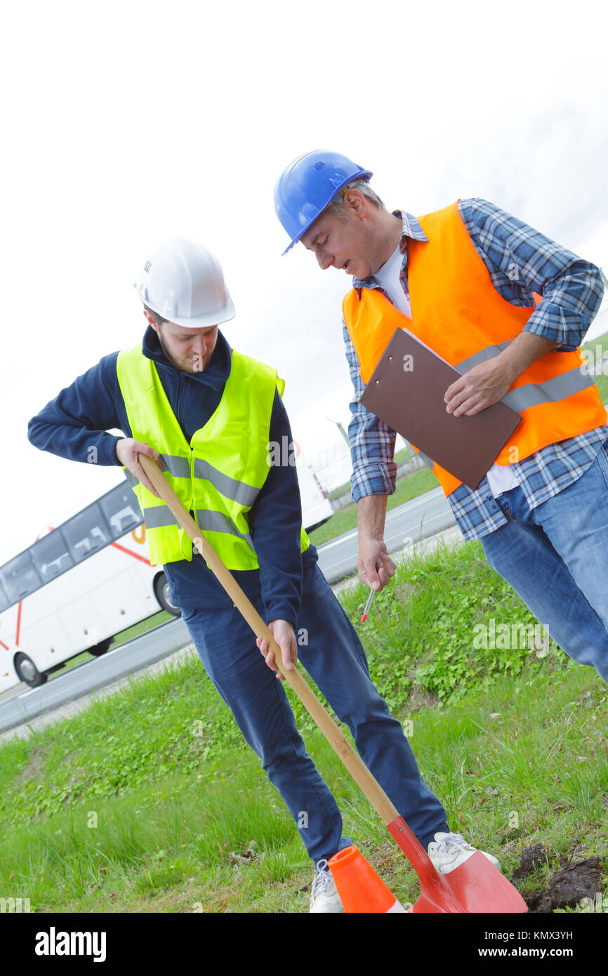 2 men employees digging a hole in the grass Stock Photo - Alamy