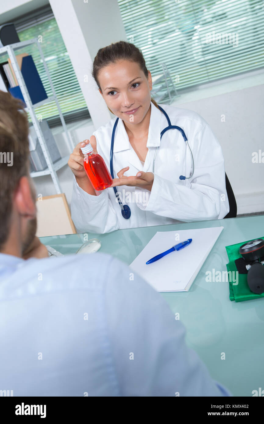 doctor showing bottle of red liquid to patient Stock Photo - Alamy
