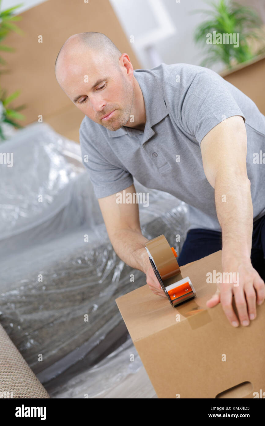 young man sealing cardboard boxes with duct tape Stock Photo - Alamy