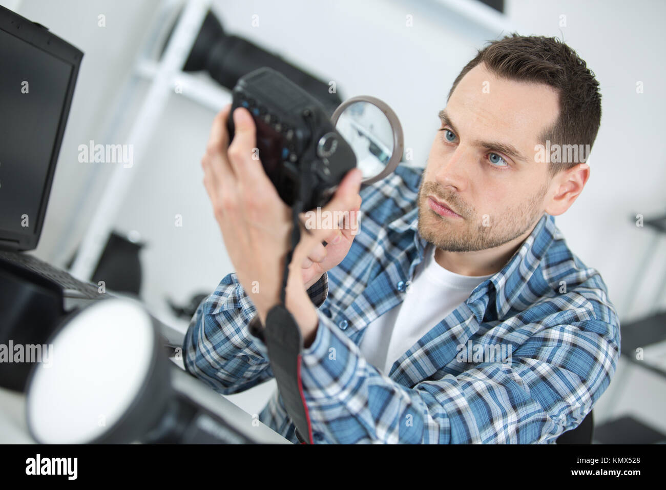 Man looking at camera body with magnifying glass Stock Photo - Alamy