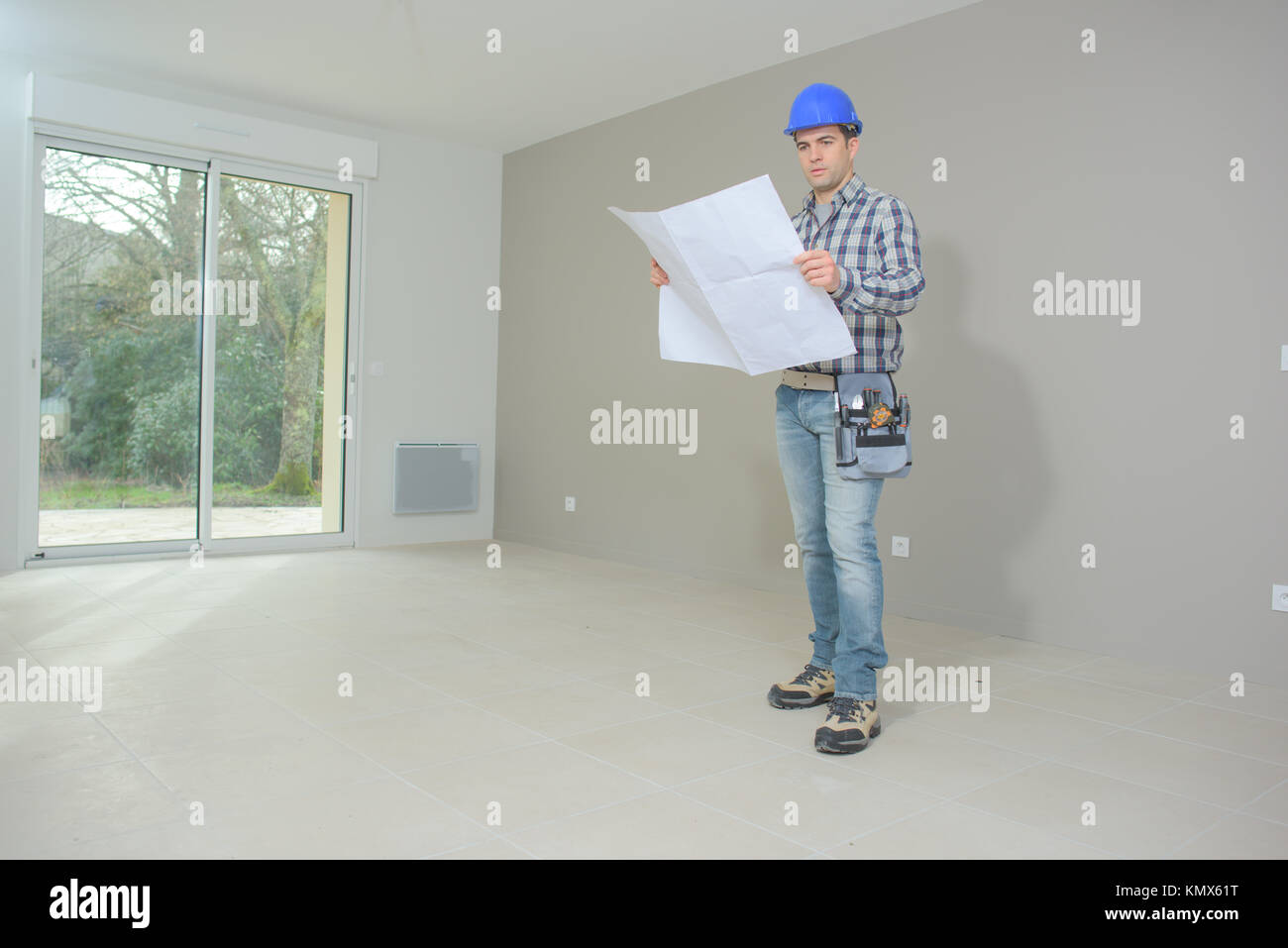 male contractor holding blueprints in empty room Stock Photo - Alamy