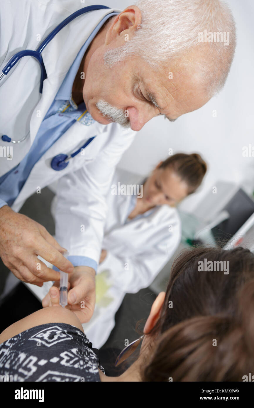 senior male doctor giving an injection to a patient Stock Photo - Alamy