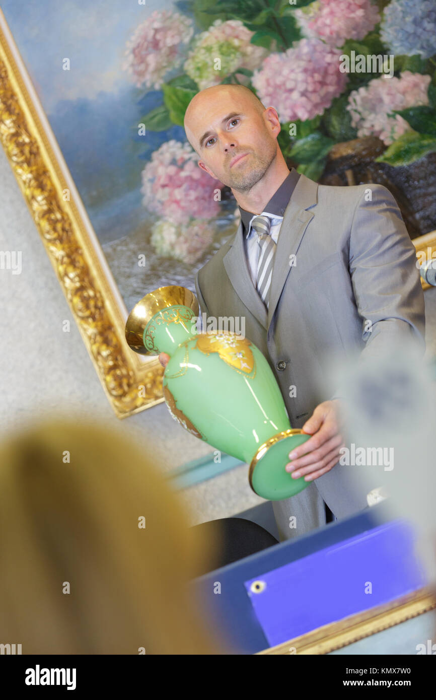 auctioneer holding antique vase during auction Stock Photo - Alamy