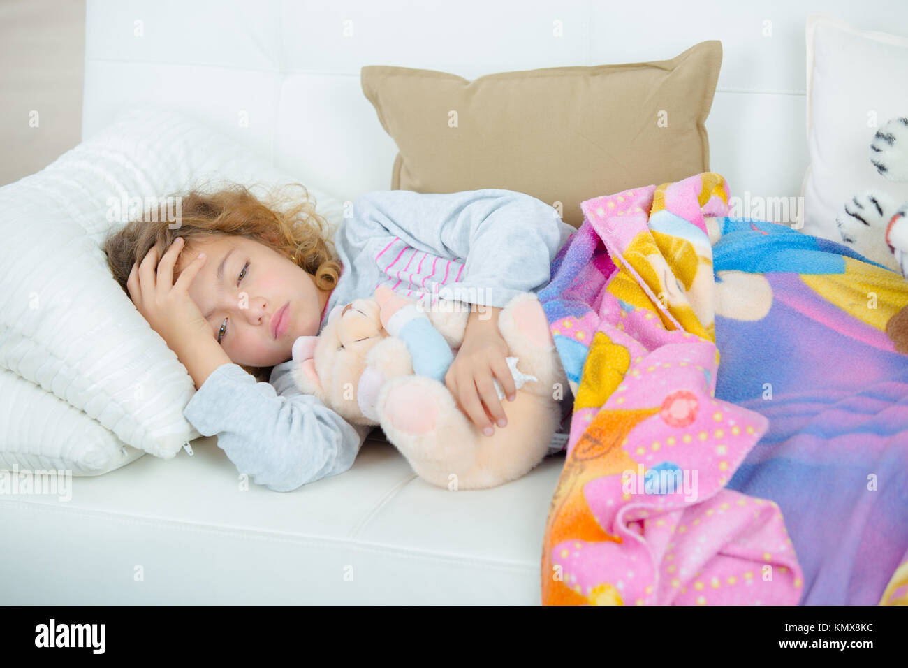 Child layed on couch, holding her head Stock Photo - Alamy