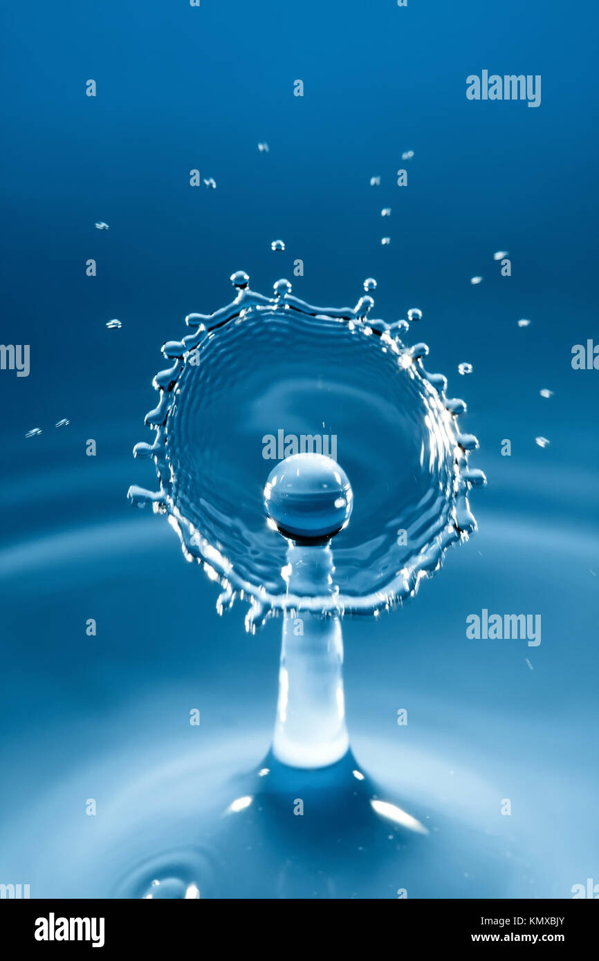 water drop falls downwards breaking about a drop Stock Photo - Alamy