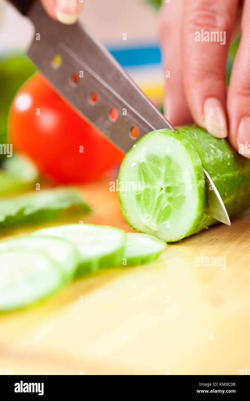 Woman's hands cutting cucumber, behind fresh vegetables Stock Photo - Alamy