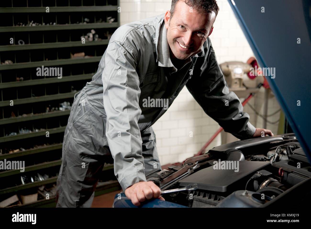 Smiling mechanic controlling car engine Stock Photo - Alamy