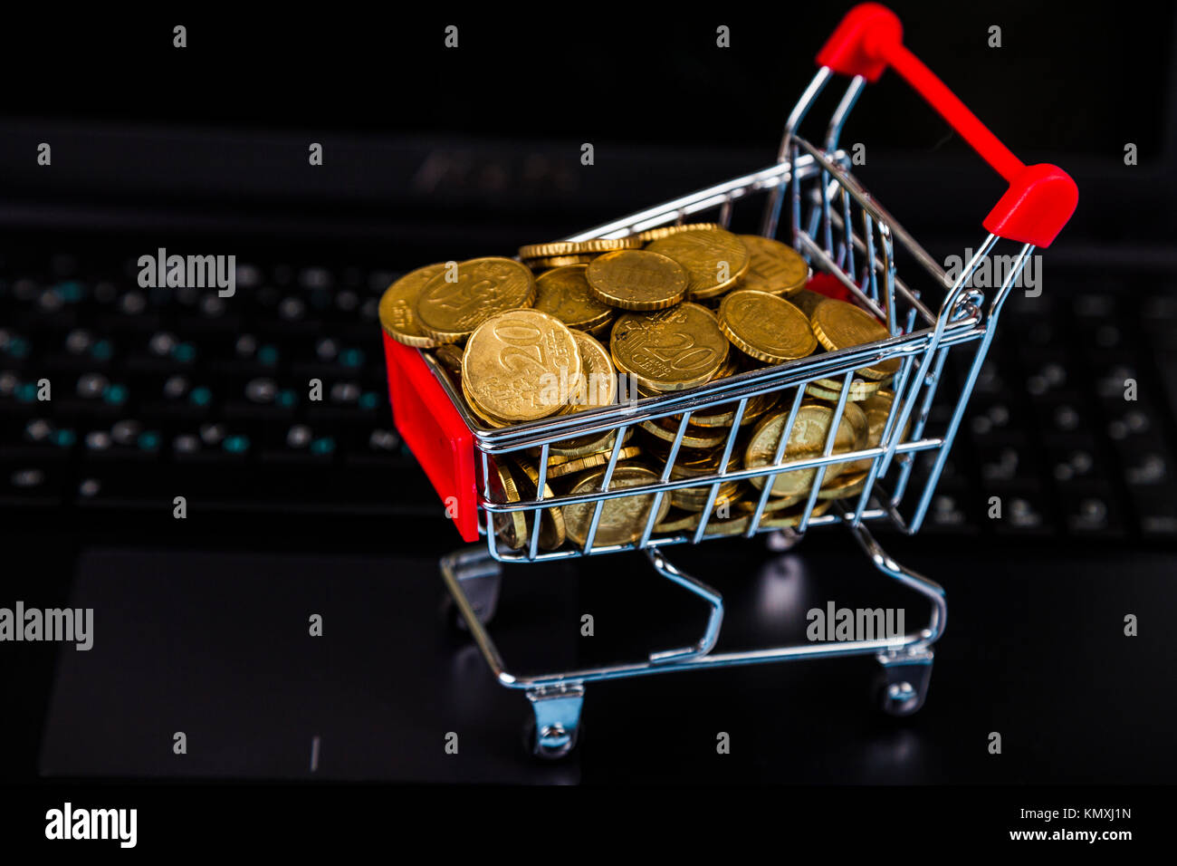 Shopping trolley with coins on a laptop Stock Photo - Alamy