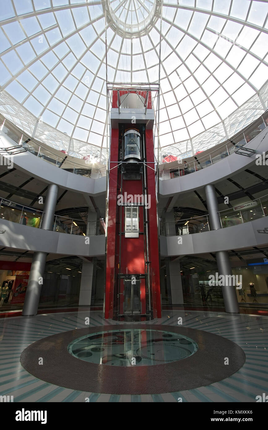 Huge hall of modern shopping centre with the glass lift, hours on a ...