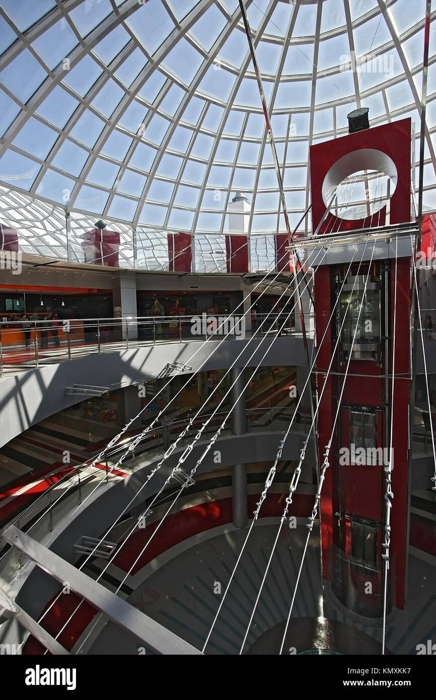 Huge hall of modern shopping centre with the glass lift, hours on a ...
