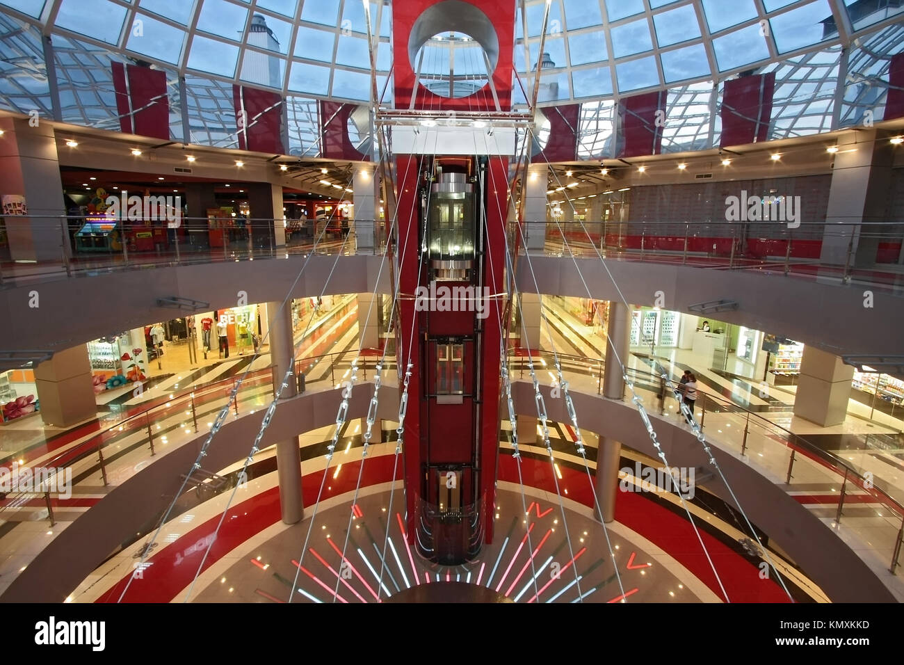 Huge hall of modern shopping centre with the glass lift, hours on a ...