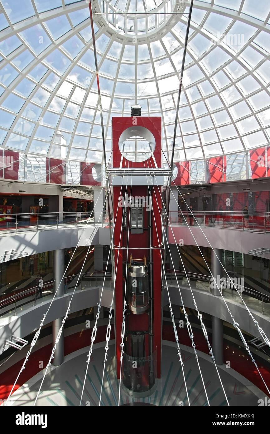 Huge hall of modern shopping centre with the glass lift, hours on a ...