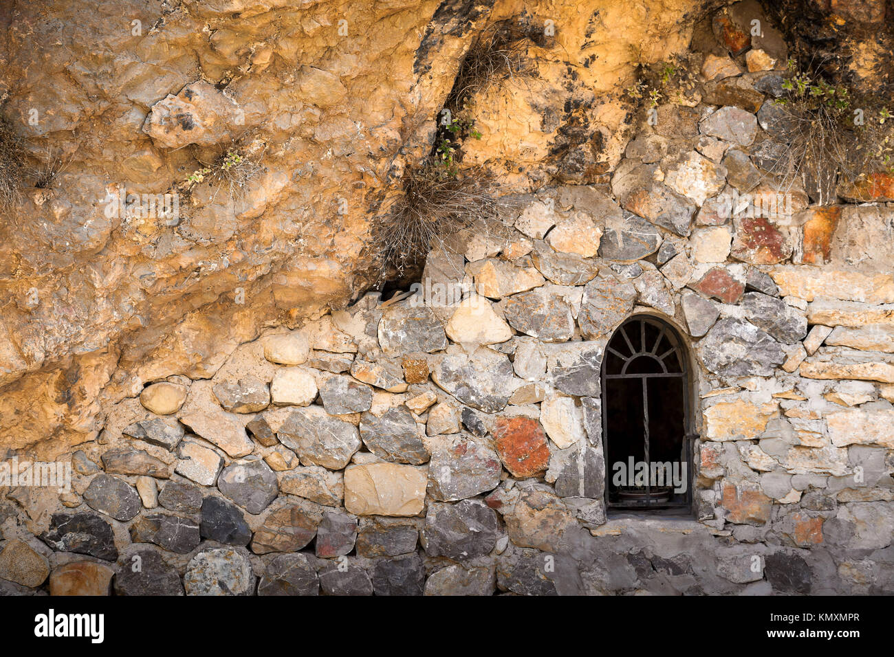 The stone wall with a window closing a grotto in the rock Stock Photo ...