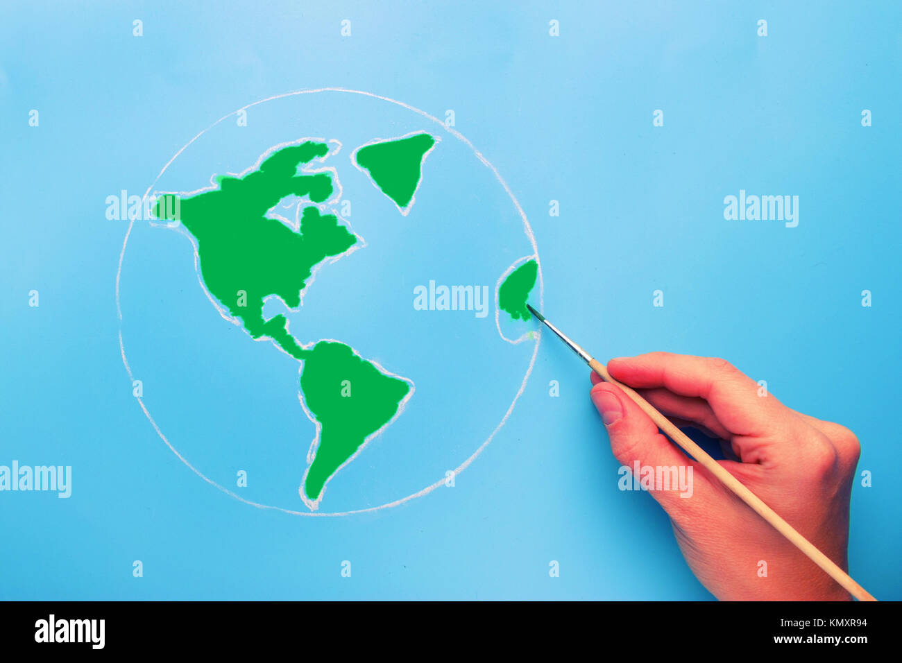 hand with brush painting world map in green color. go green concept ...
