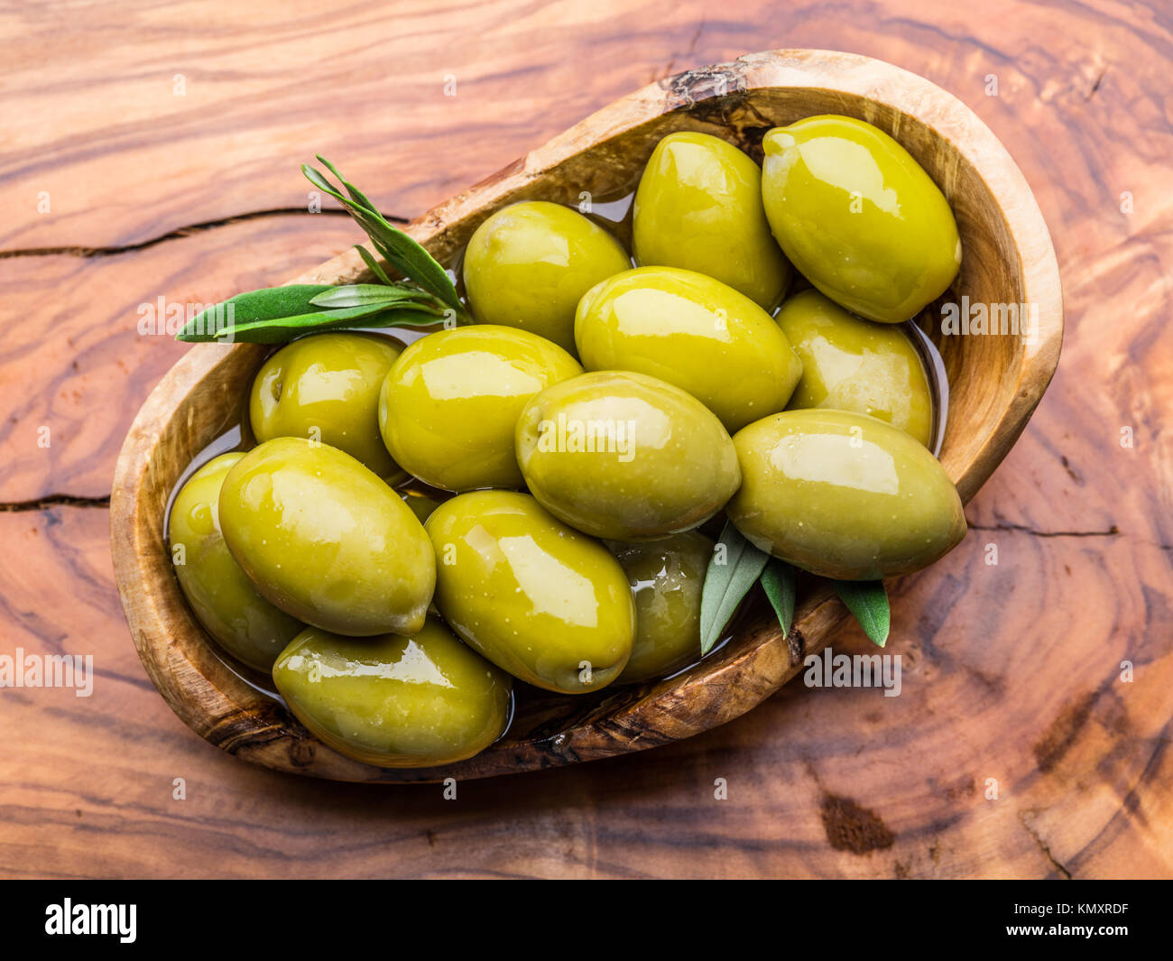 Whole table olives in the wooden bowl on the table. Top view Stock ...