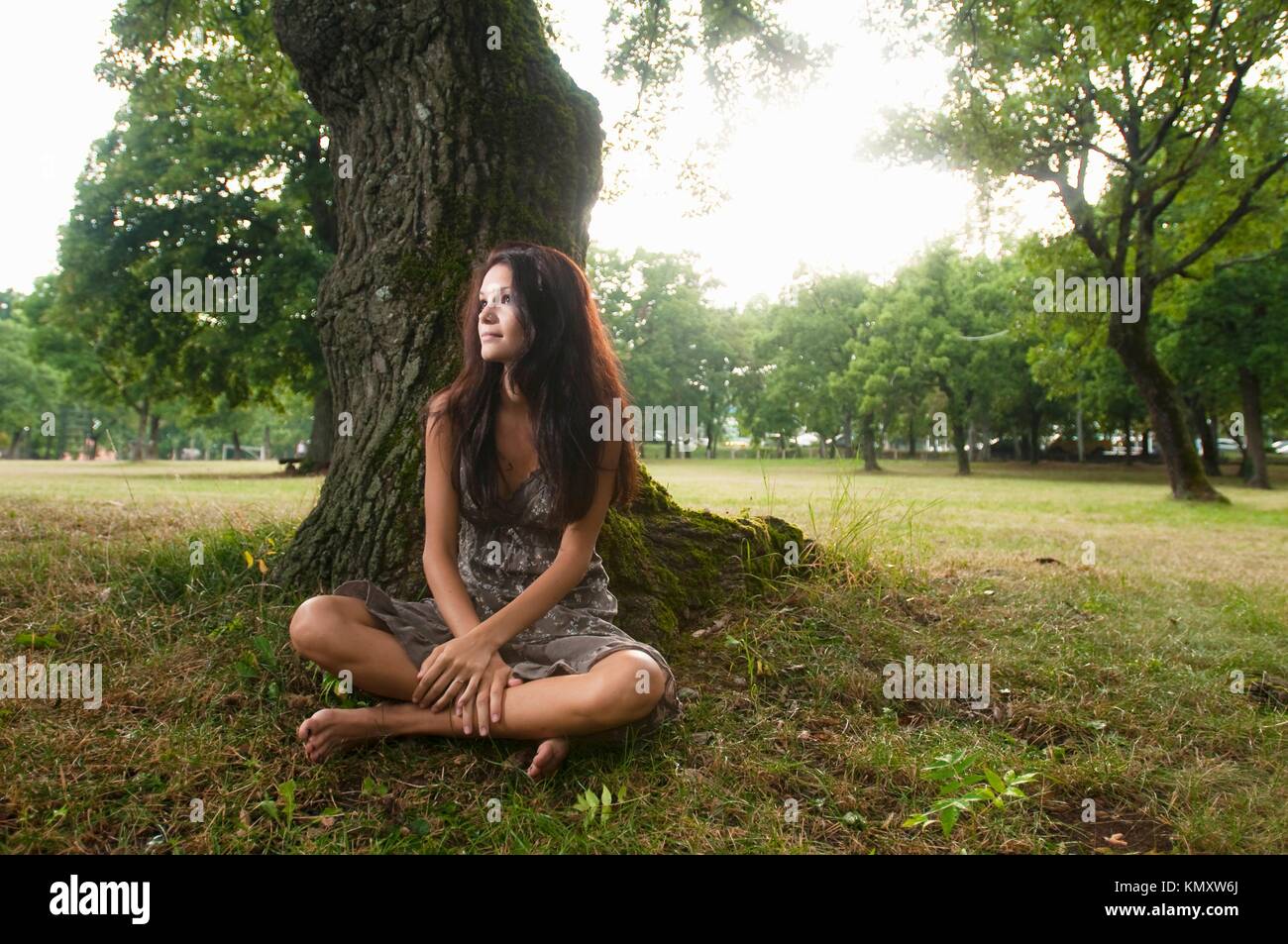 Pure, natural, beautiful young woman in nature, sitting under a tree ...