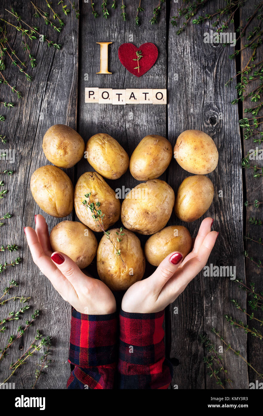 Woman holding Potato with thyme on rustic wooden background from the ...