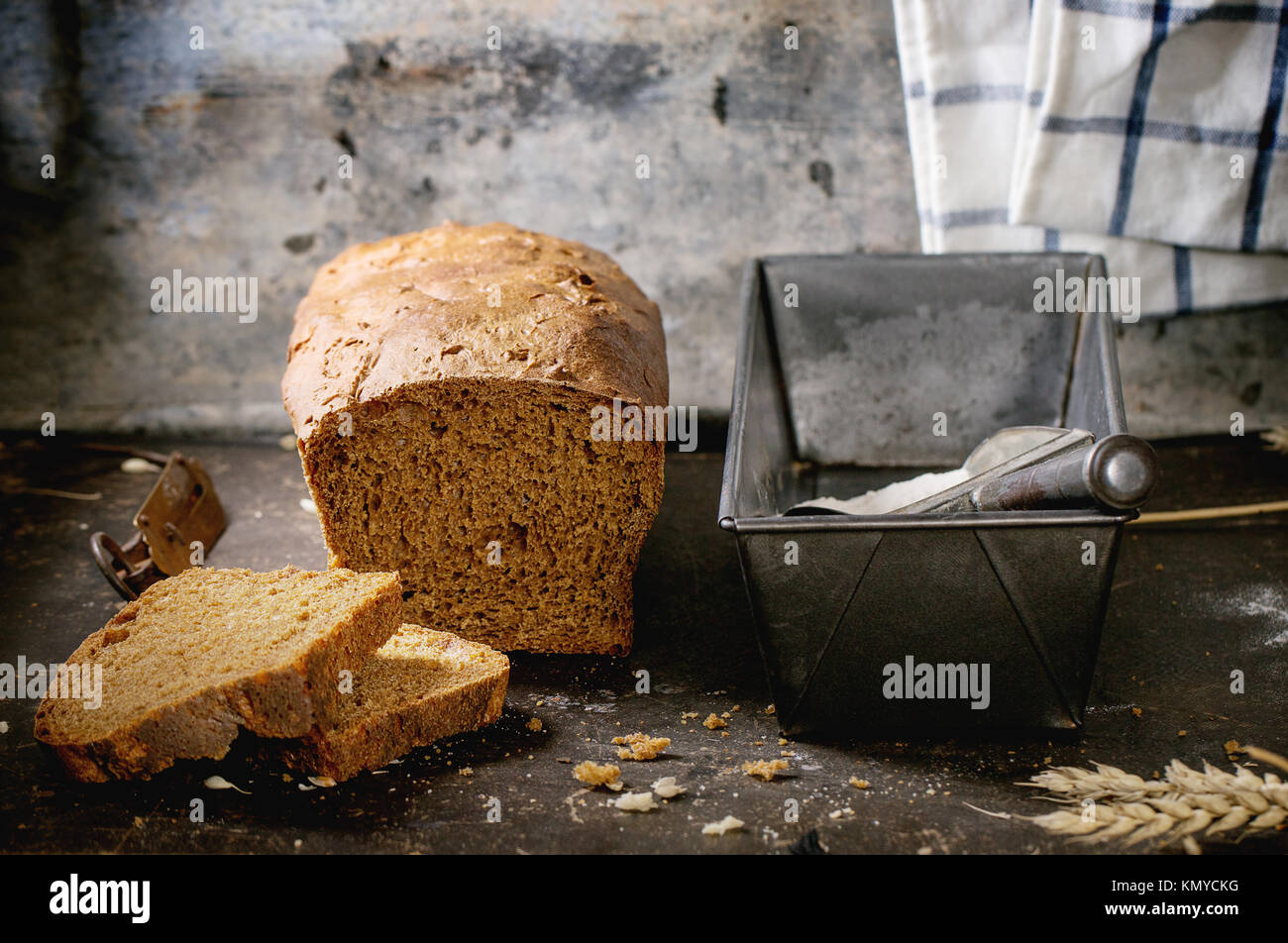 Loaf of fresh homemade rye bread with wheat seeds and flour over dark ...