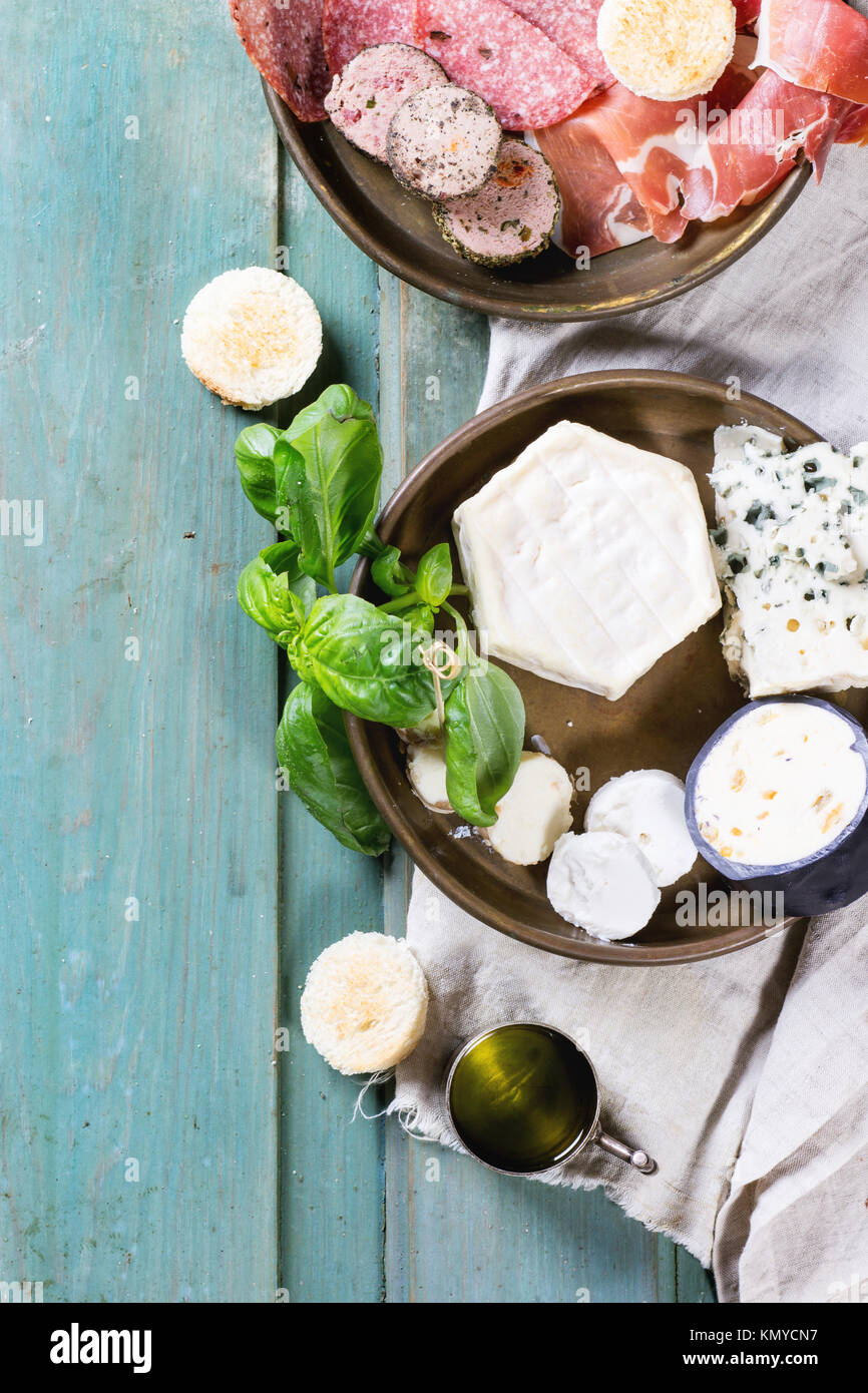 Metal plates with cheese and sausage variations with fresh basil and ...