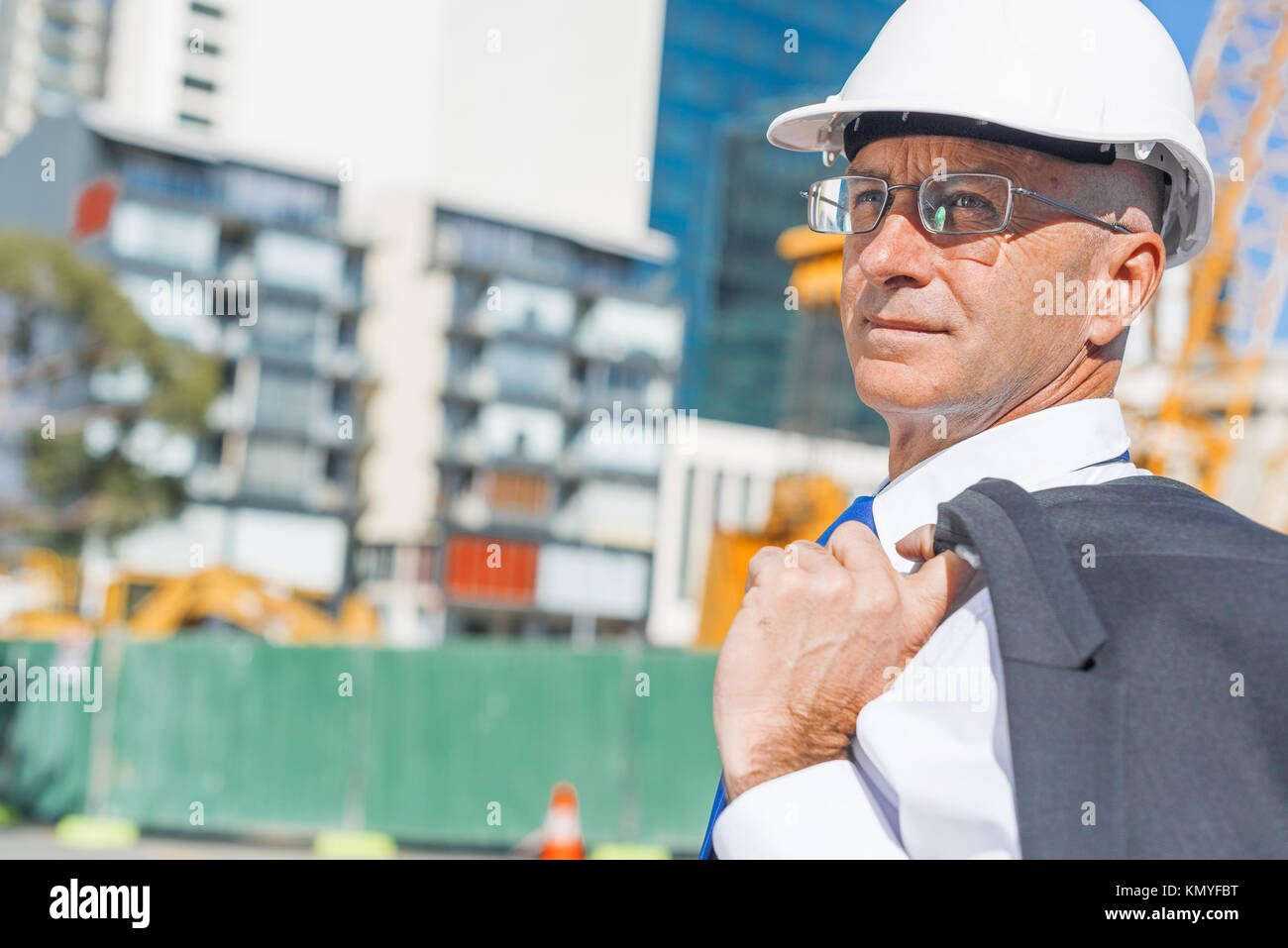 Senior elegant builder man in suit at construction site on sunny summer ...