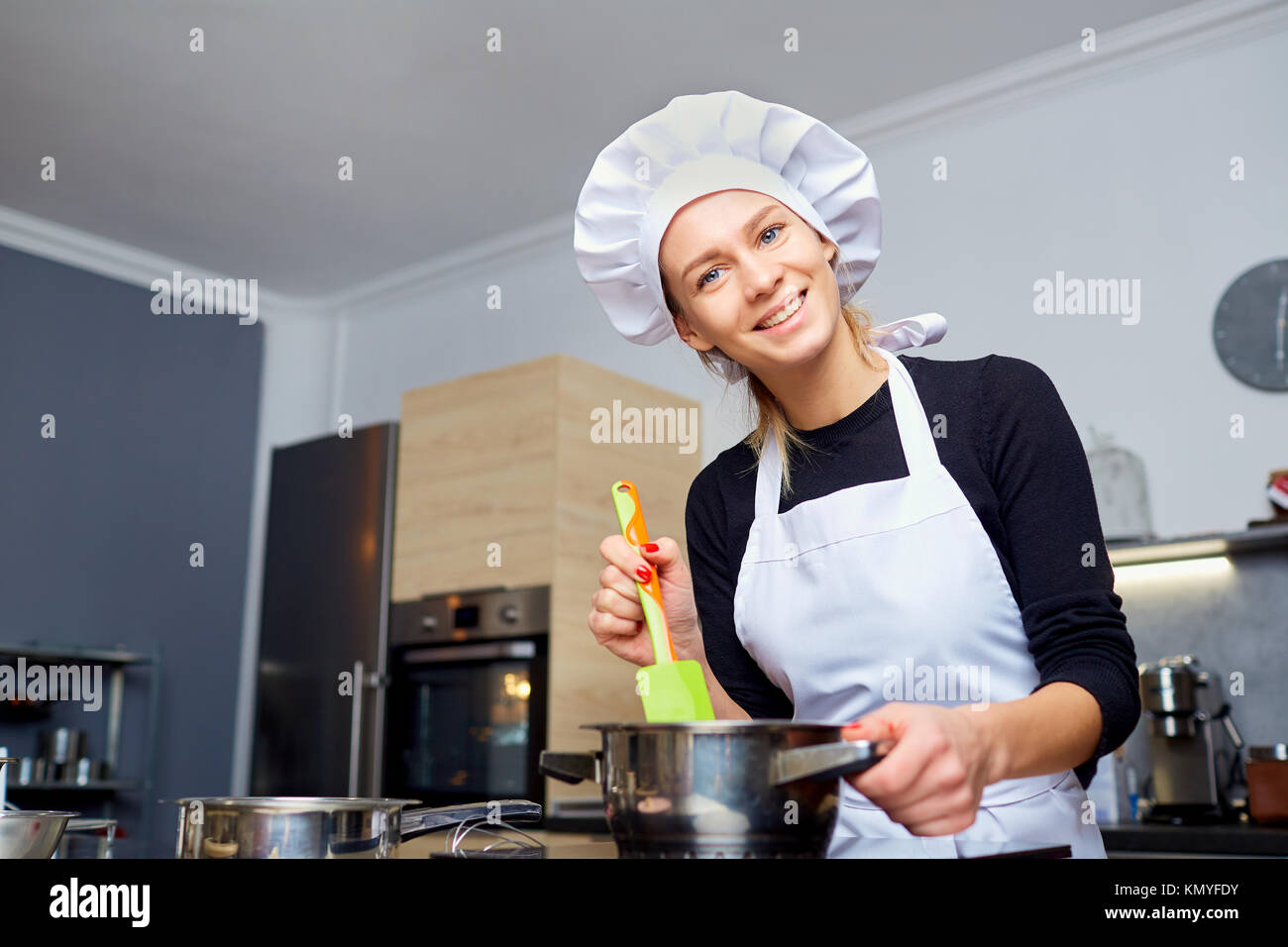 A chef woman in a hat is cooking in the kitchen Stock Photo - Alamy