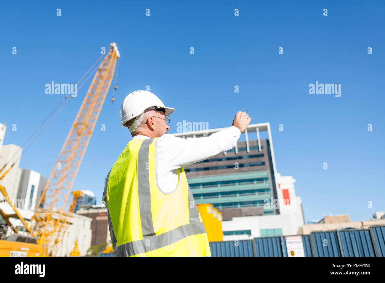 Senior foreman in glasses doing his job at building area on sunny day ...