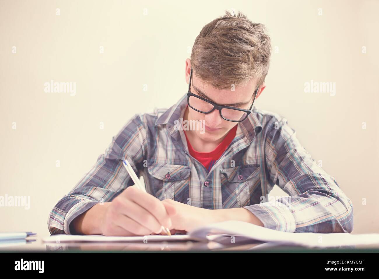 The student with glasses teenager does a homework, he writes in the ...