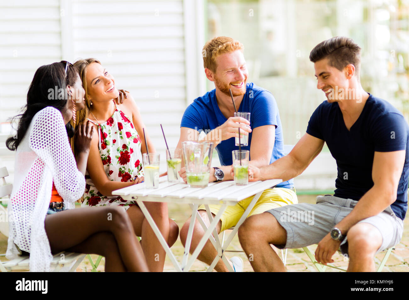 Young and happy friends sitting talking at a table Stock Photo - Alamy