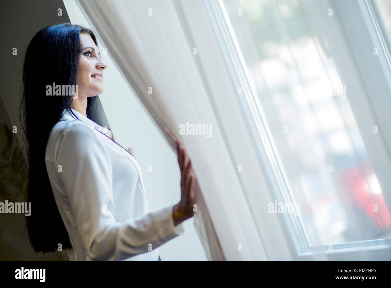 Happy beautiful woman staring out the window Stock Photo - Alamy