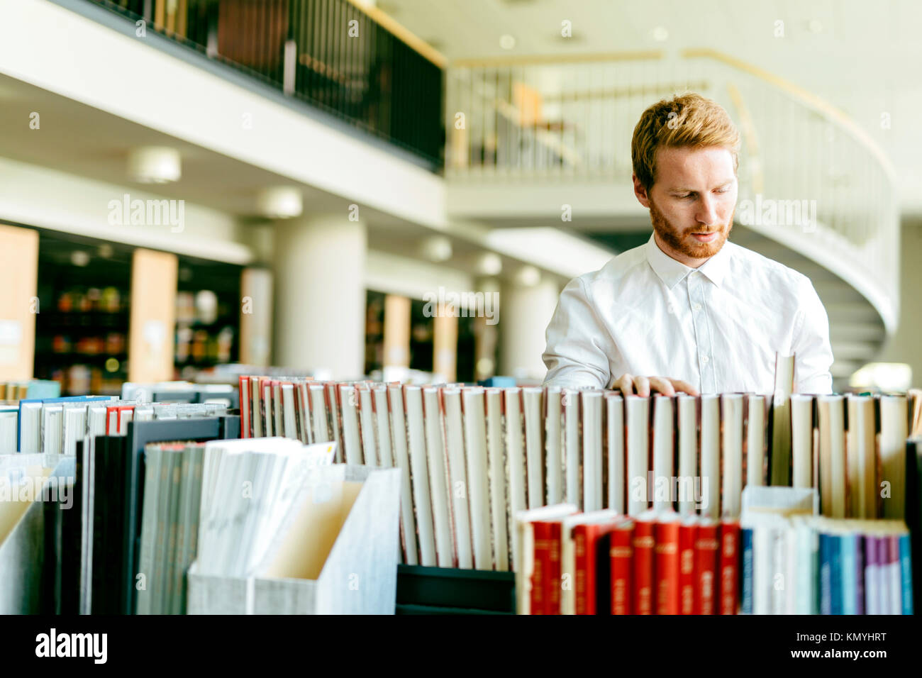 Handsome student searching for a book in a library Stock Photo - Alamy