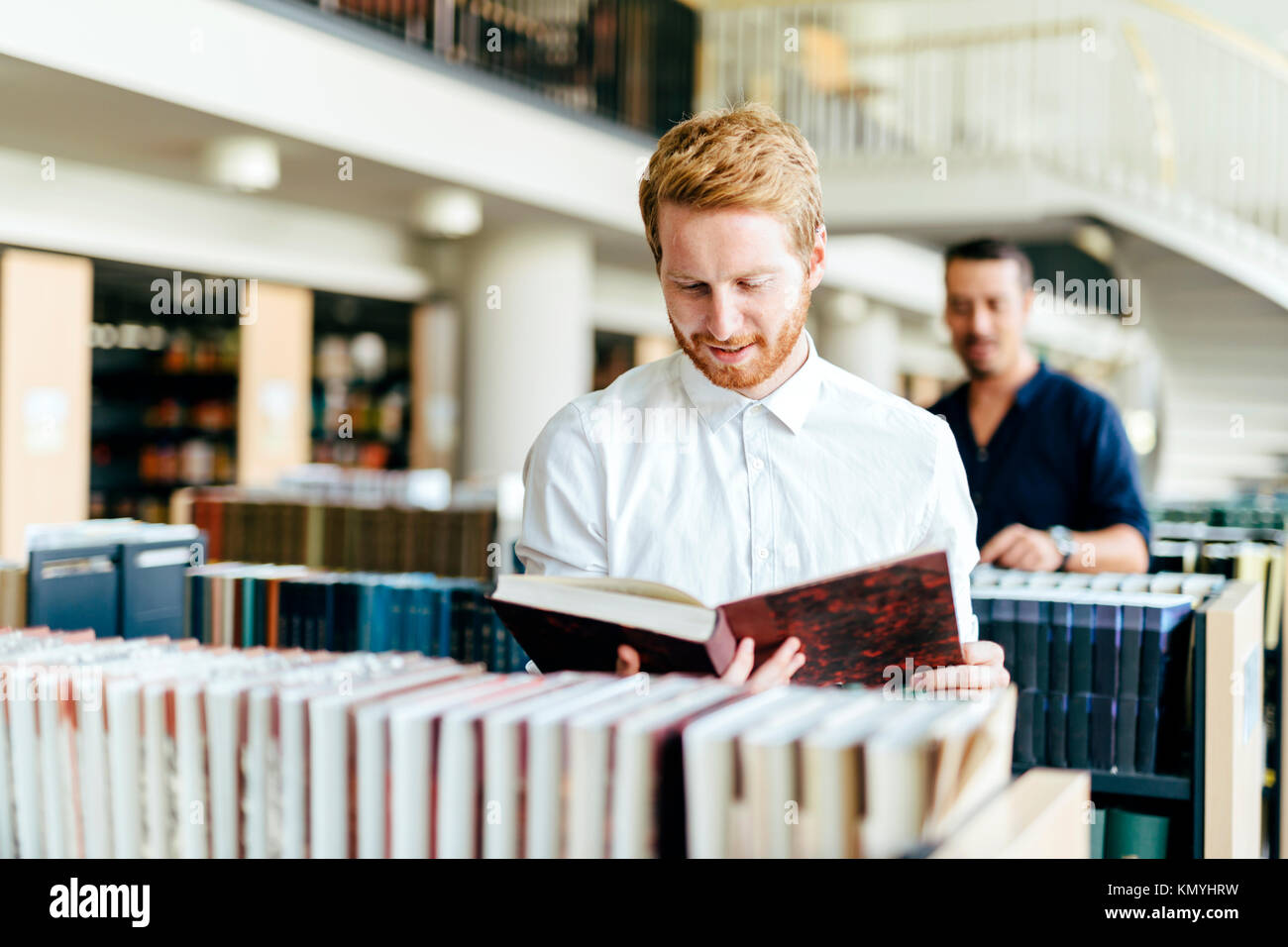 Handsome student reading a book in a library Stock Photo - Alamy
