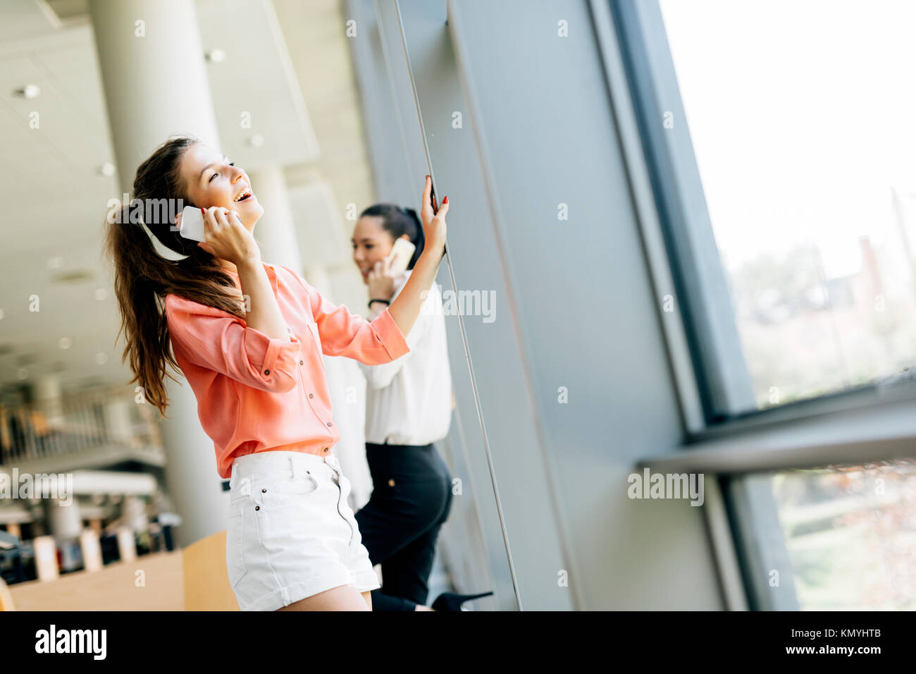 Beautiful women using phones and talkin during break Stock Photo - Alamy