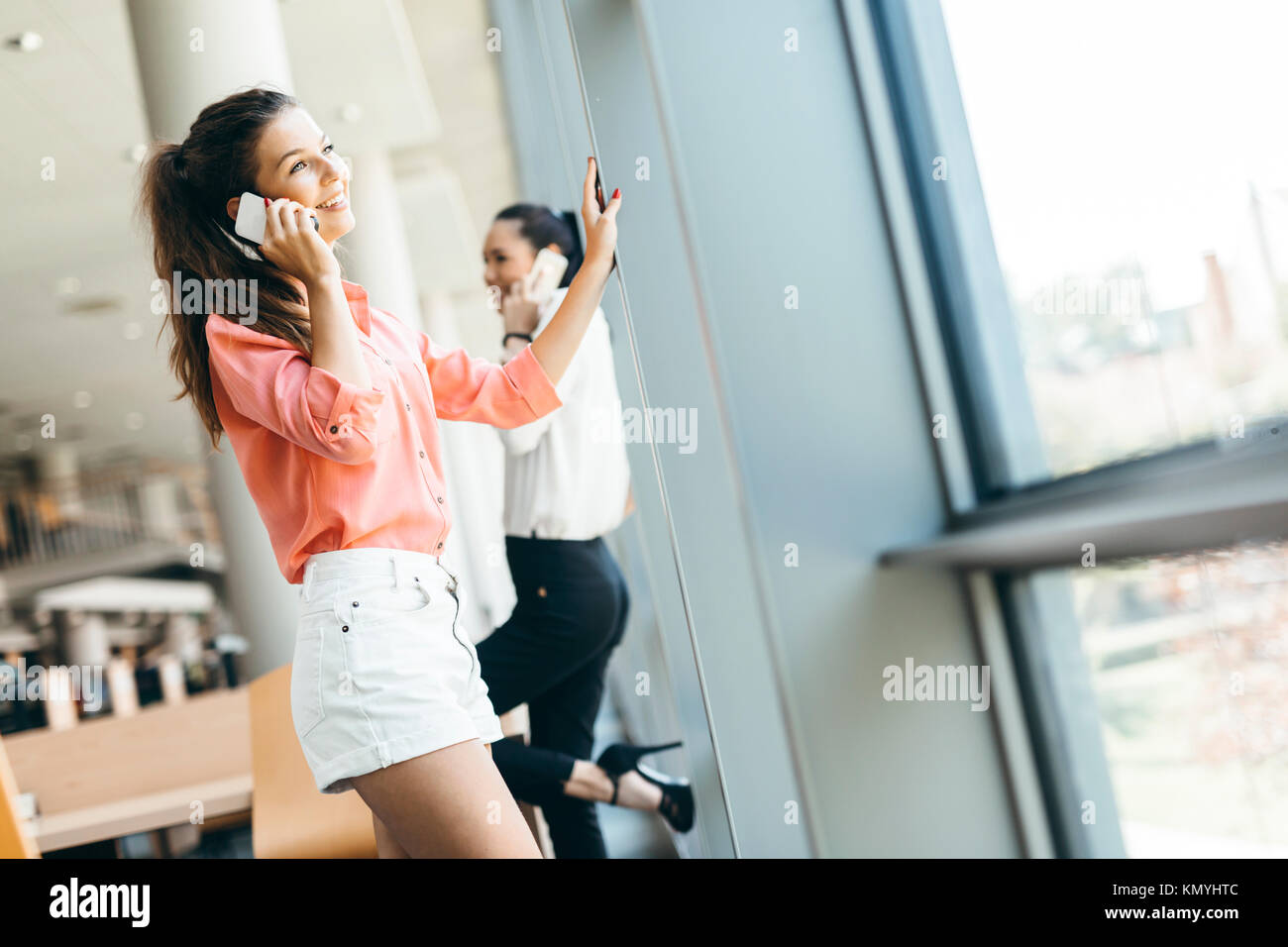 Beautiful women using phones and talkin during break Stock Photo - Alamy