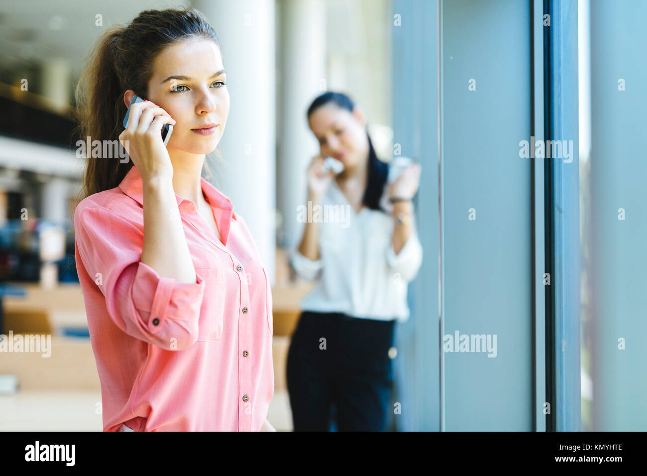 Beautiful women using phones and talkin during break Stock Photo - Alamy