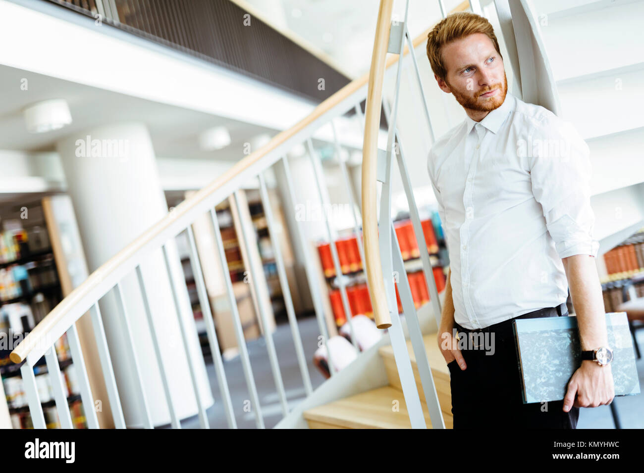 Handsome intelligent guy reading a book in a library Stock Photo - Alamy