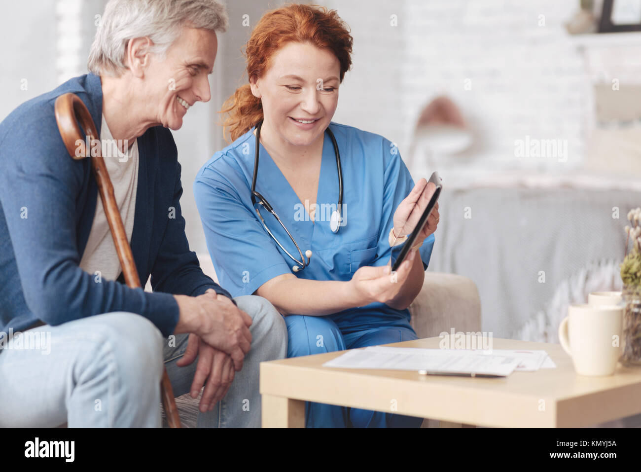 Friendly senior patient and nurse looking tablet computer Stock Photo ...