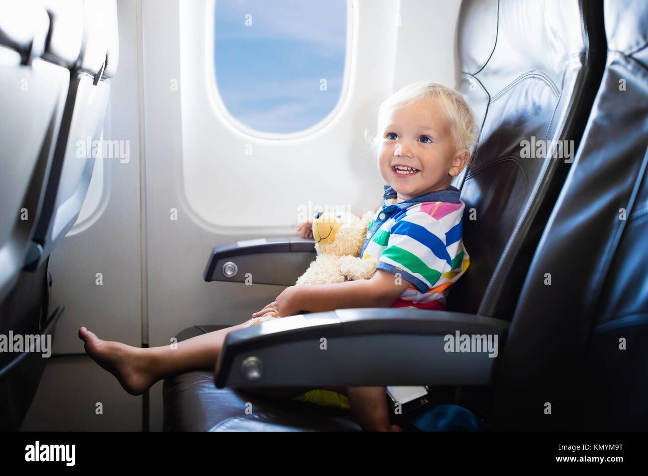 Child in airplane. Kid in air plane sitting in window seat. Flight ...
