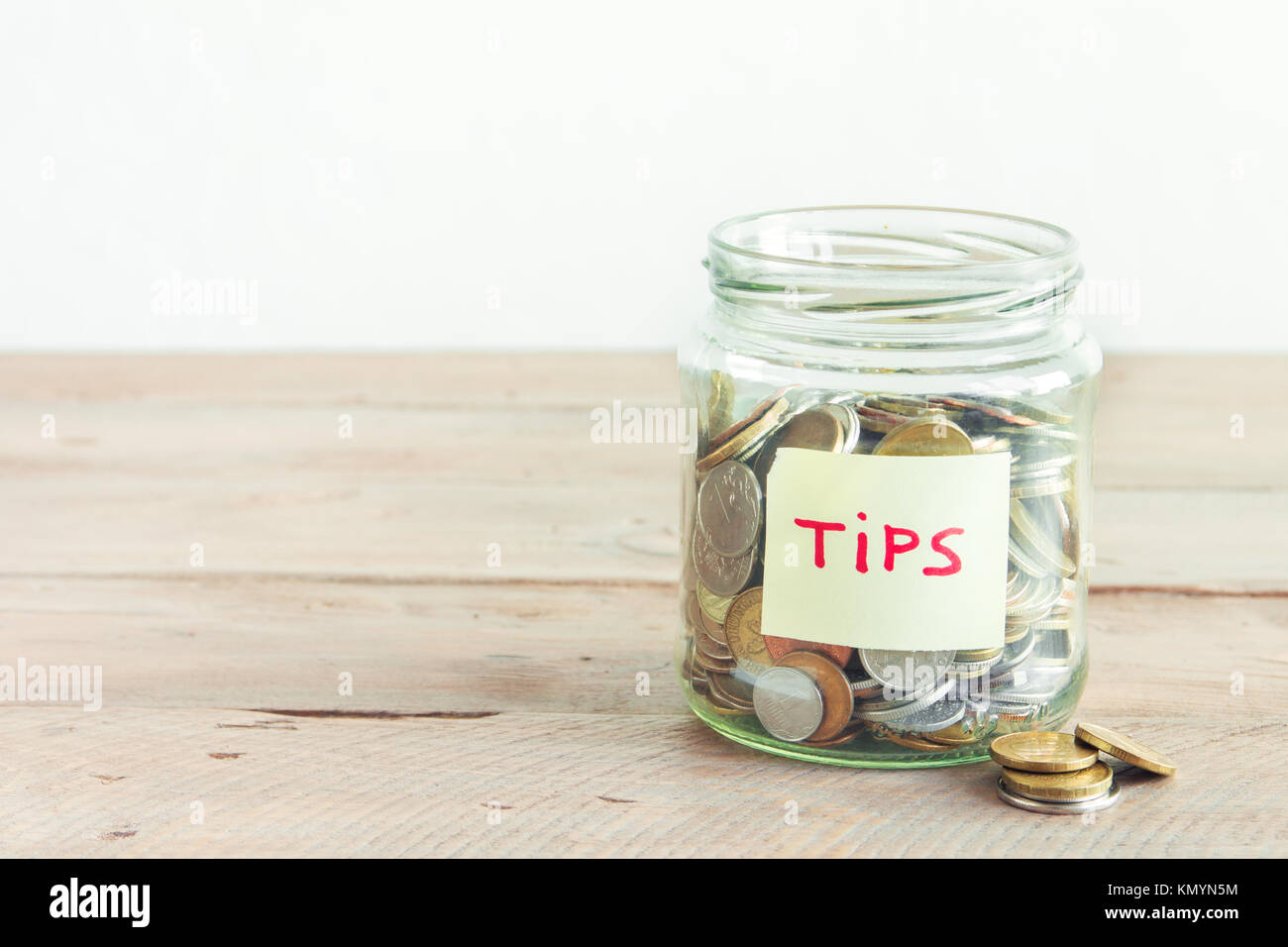 Coins in glass jar with Tips label. Money savings, tips and donation ...