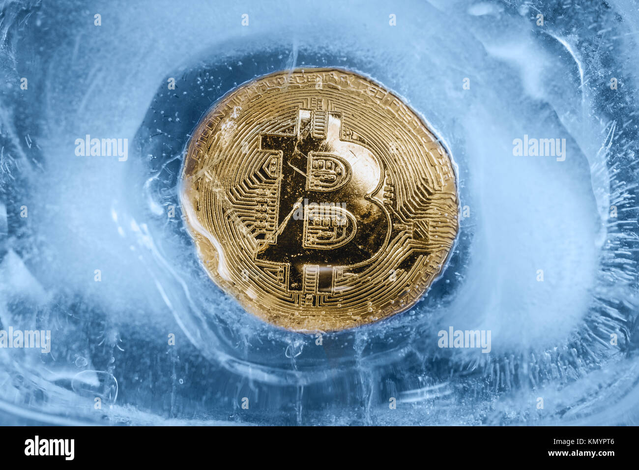 The gold coin of cryptocurrency Bitcoin is freezing in the blue ice ...